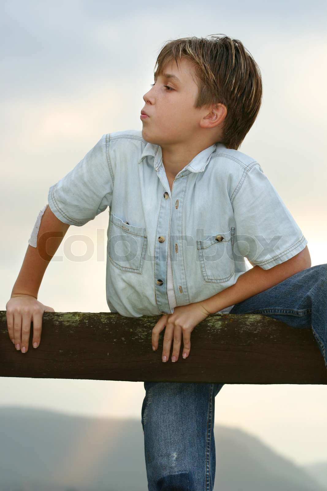 Boy climbs over a fence on an overcast late afternoon | Stock image ...