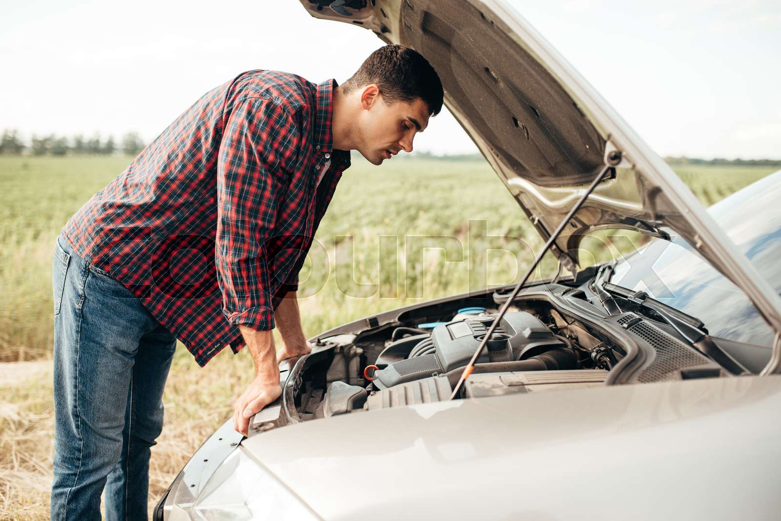 Tired man tries to repair a broken car | Stock image | Colourbox