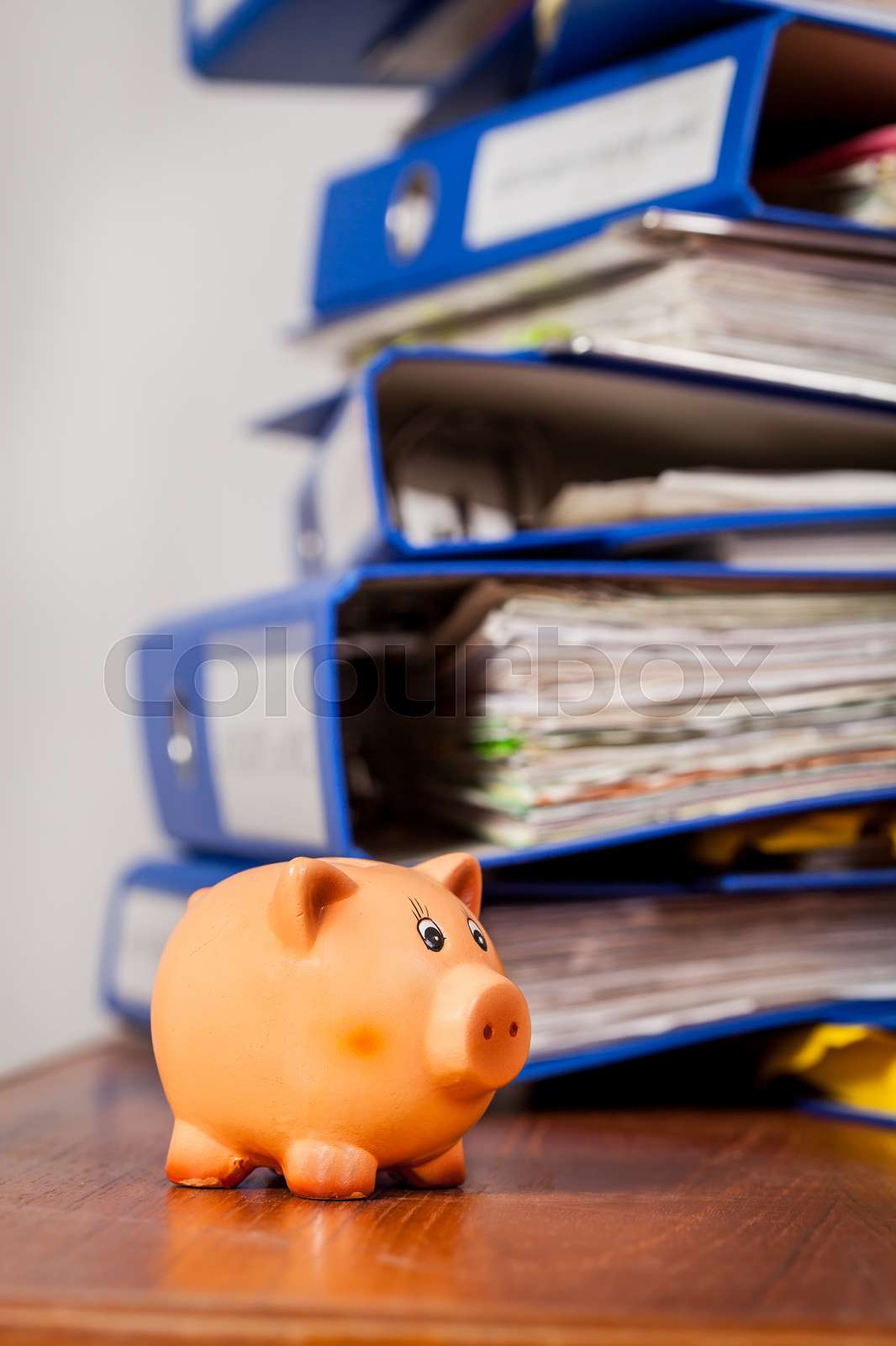Piggy bank over stack of office folders | Stock image | Colourbox