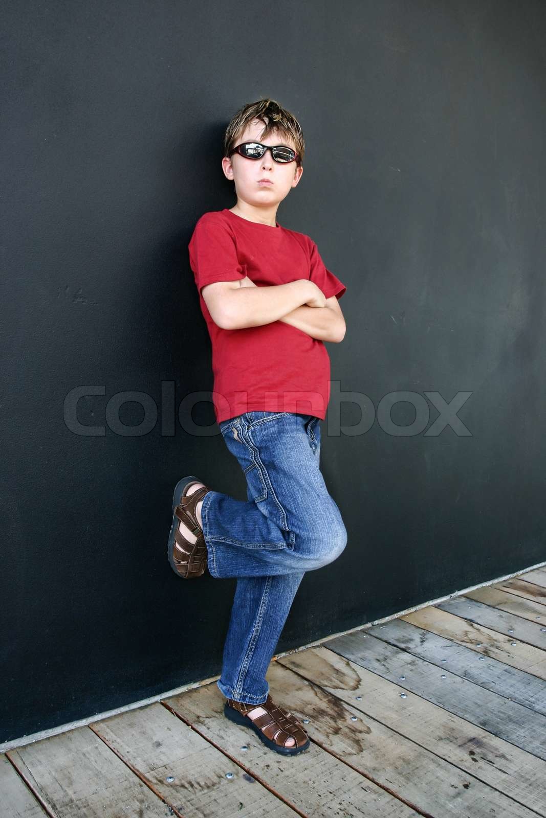 Child in jeans and t-shirt stands casually leaning partially against ...