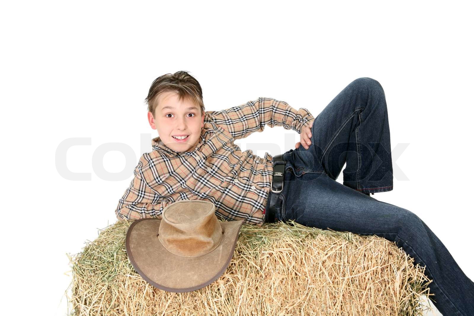 A boy from the country lays casually on a hay bale and smiles | Stock ...