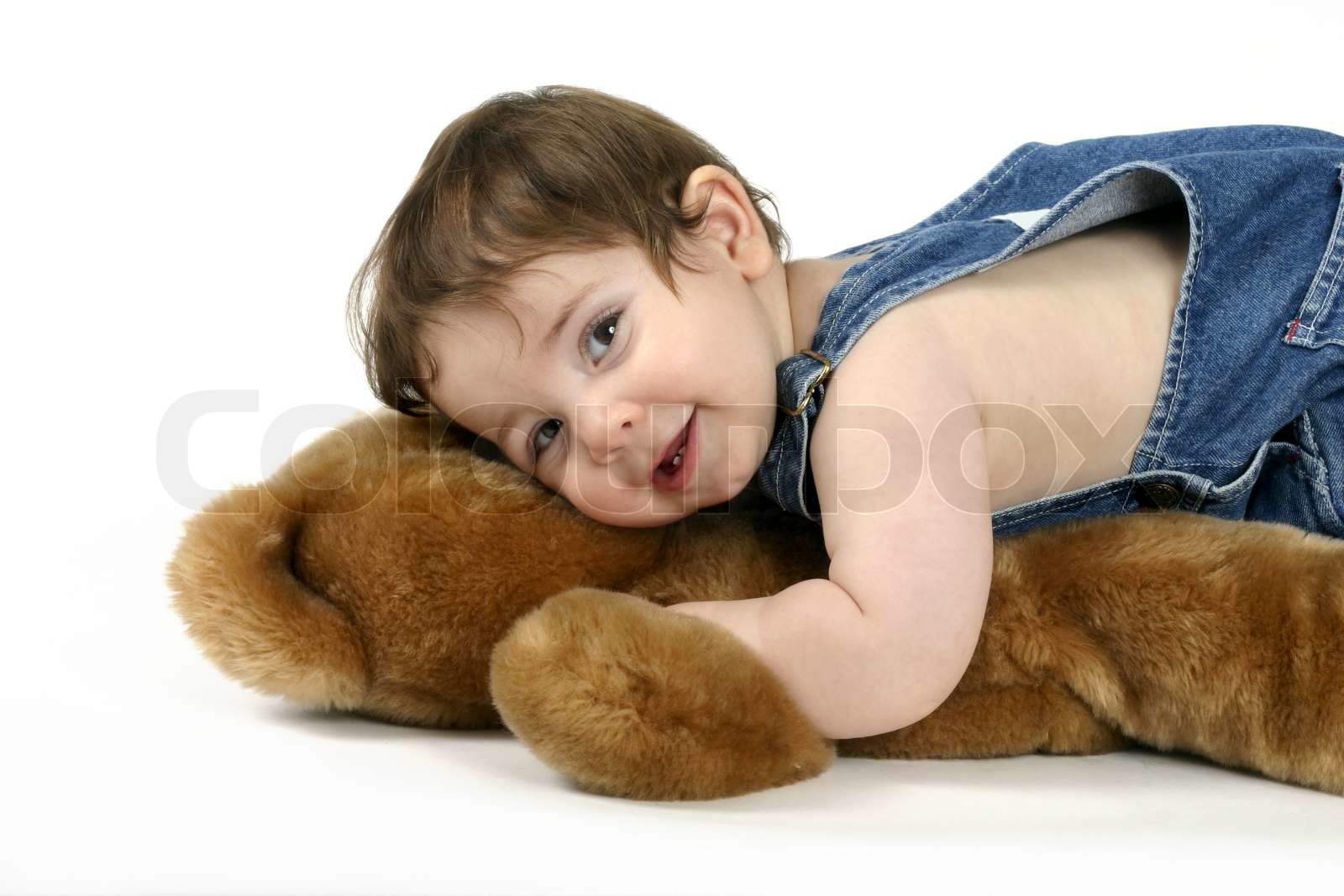 A beautiful baby cuddles a fluffy toy soft brown teddy bear | Stock ...
