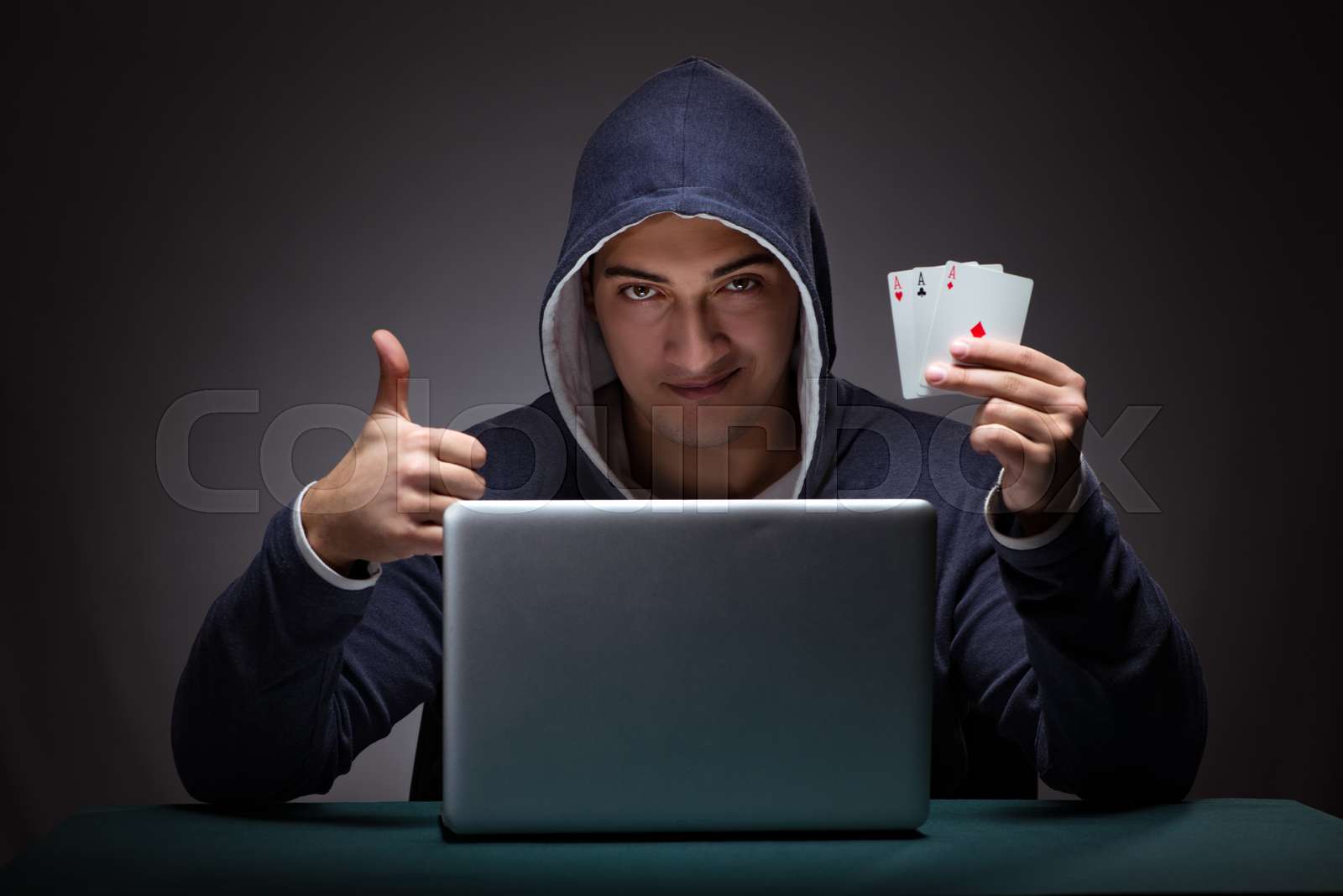 Young man wearing a hoodie sitting in front of a laptop computer ...