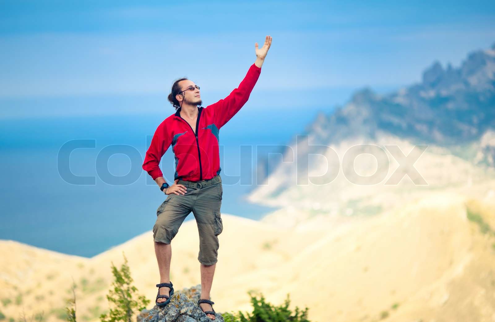 Man on top of mountain holding arm up | Stock image | Colourbox