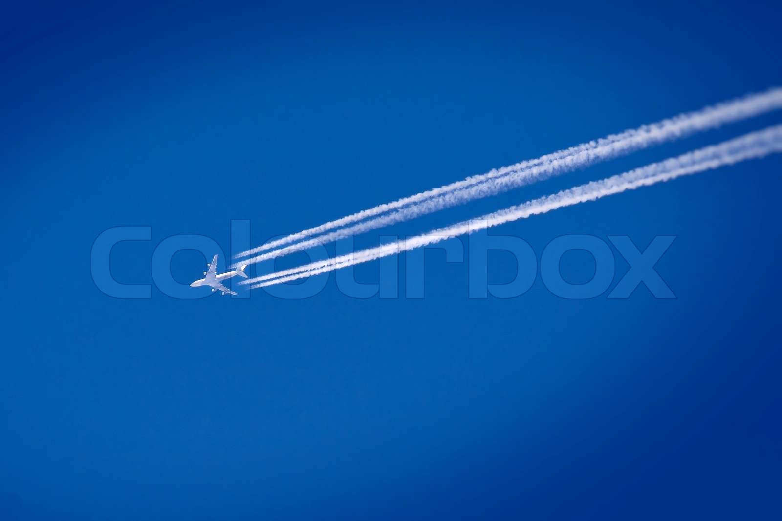 Flying airplane on the blue sky leaving white lines behind | Stock ...
