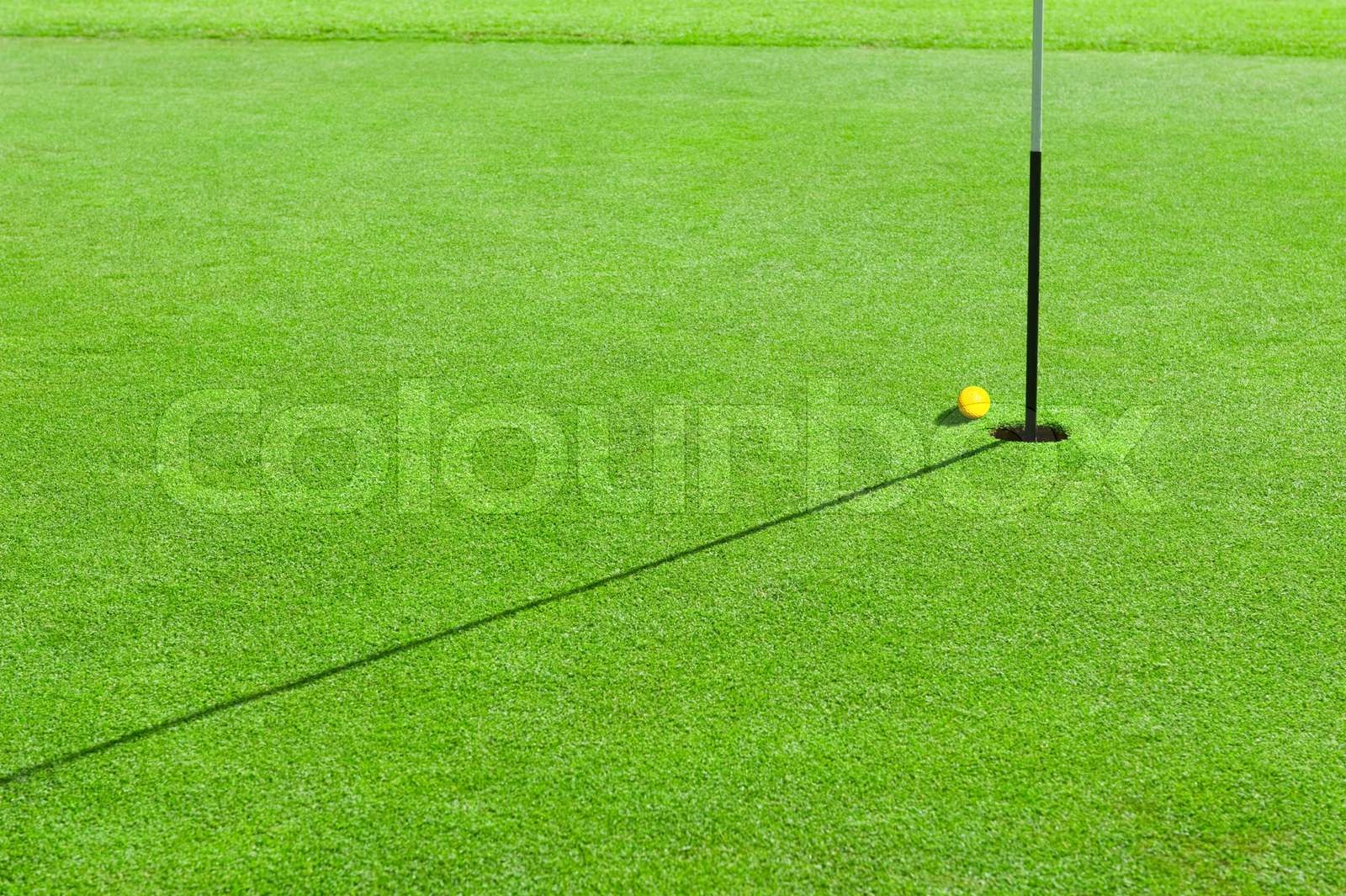 Golf bold på kanten af hullet på det grønne græs | Stock foto | Colourbox