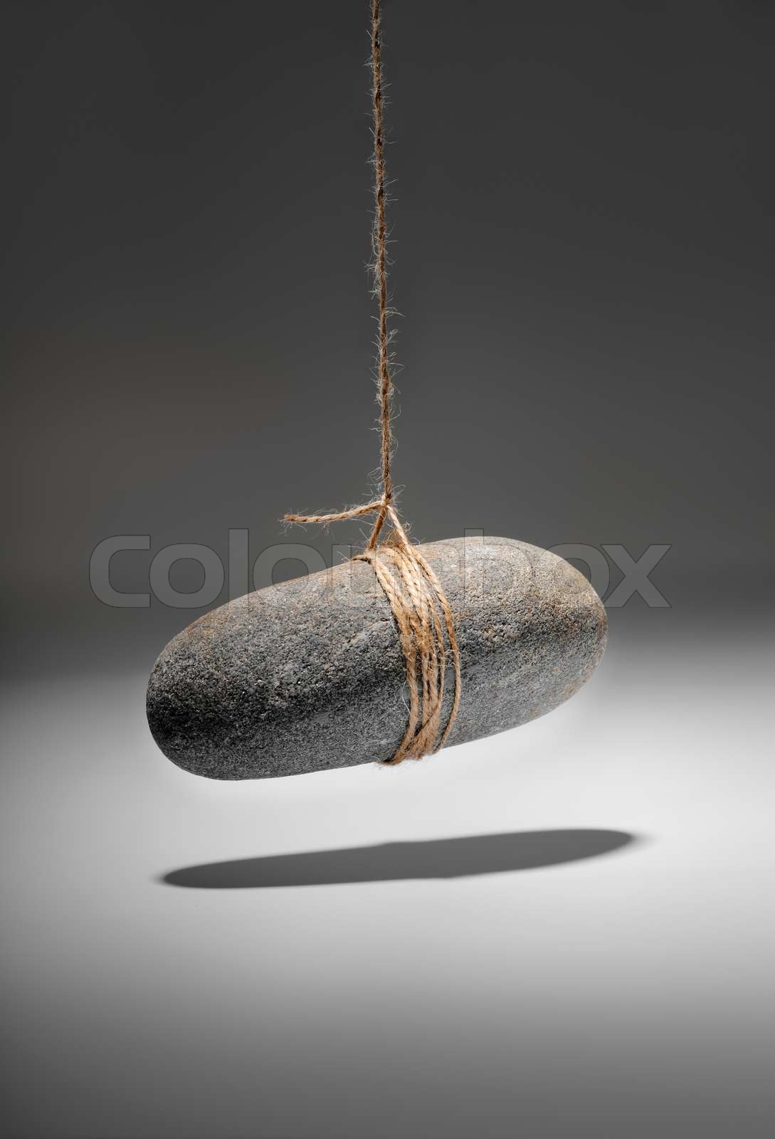 Conceptual image of a small rock hanging on a string | Stock image ...