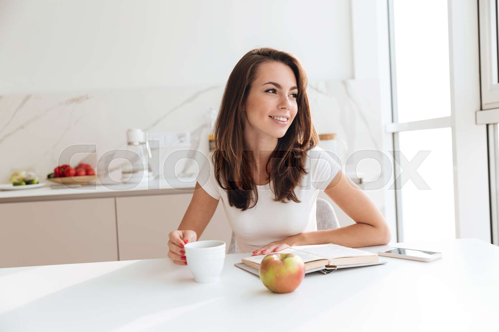 Happy young woman drinking coffee while sitting | Stock image | Colourbox