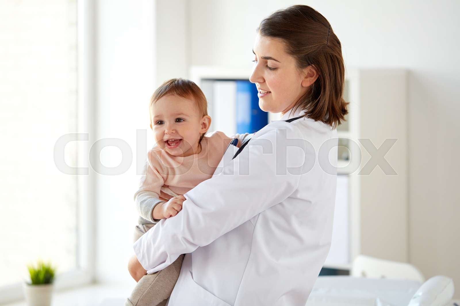 doctor or pediatrician holding baby at clinic | Stock image | Colourbox