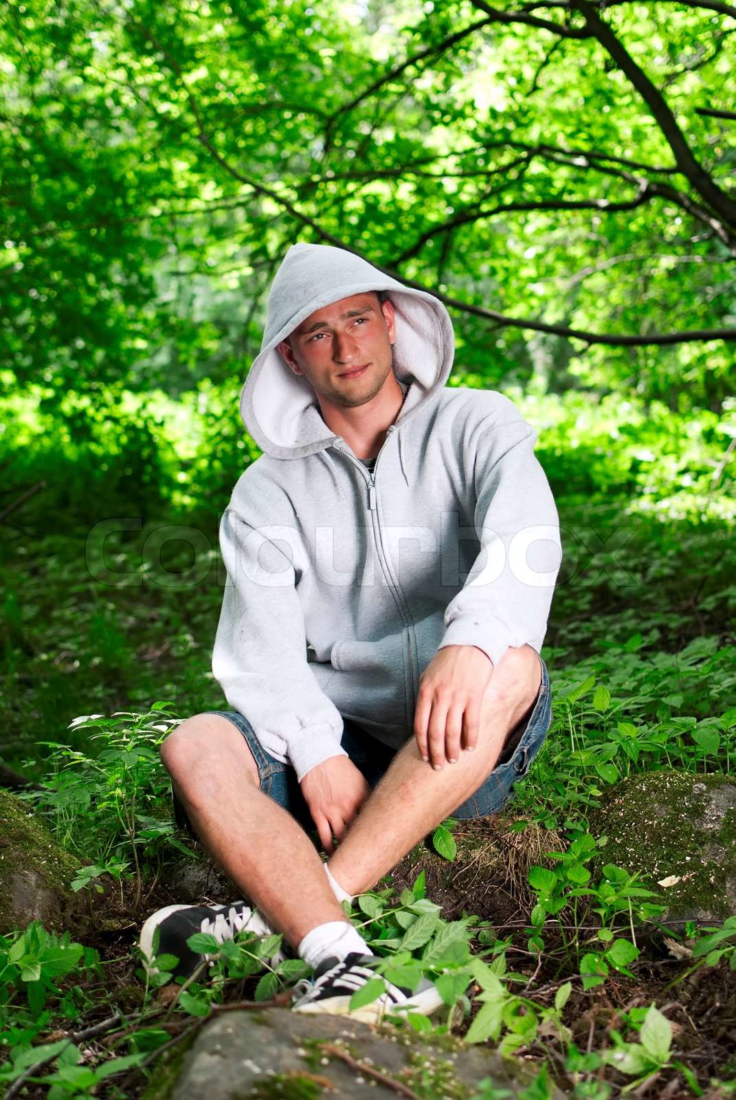 Man in sportswear sitting in the woods, in the shade | Stock image ...