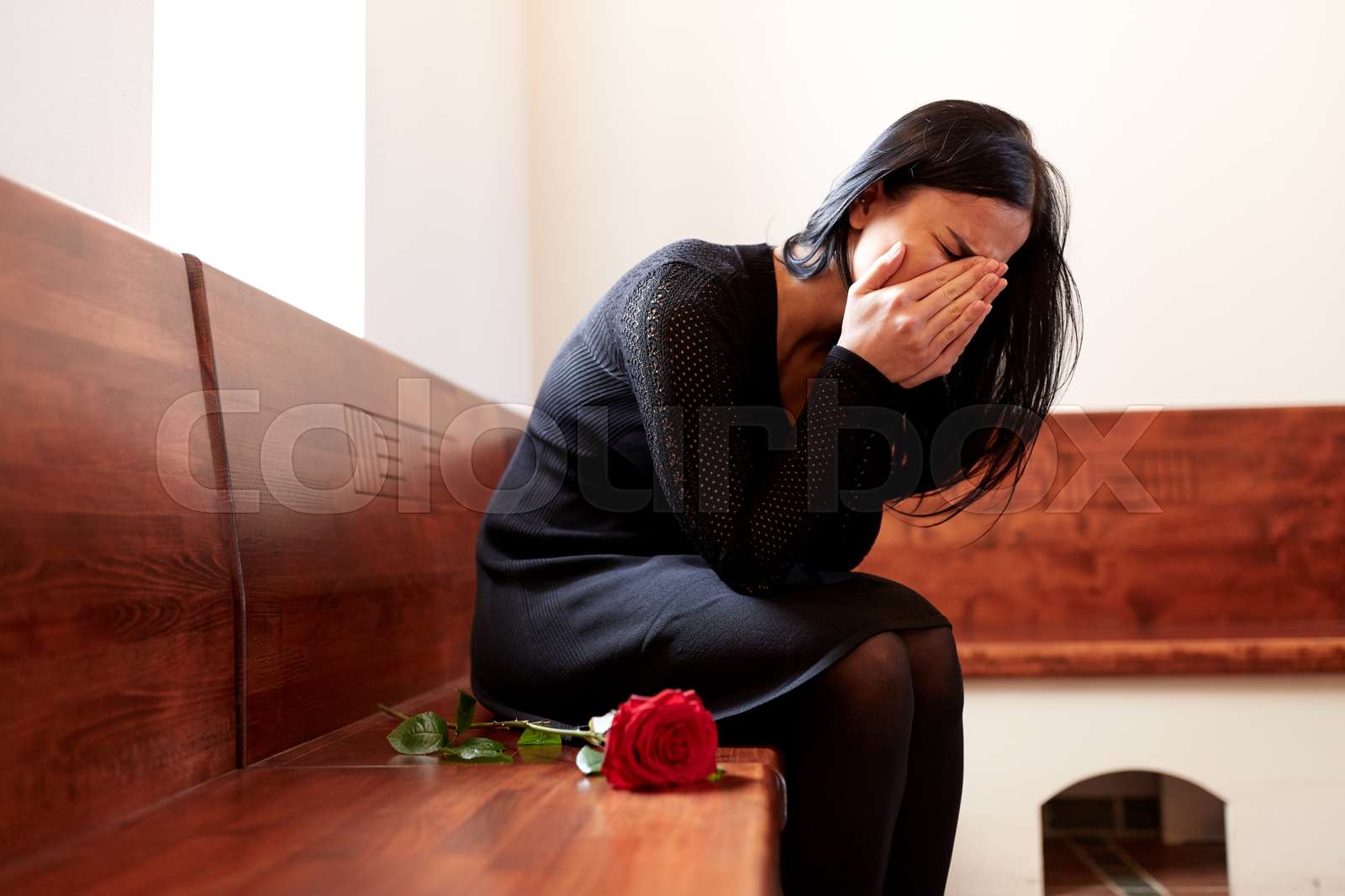 crying woman with red rose at funeral in church | Stock image | Colourbox