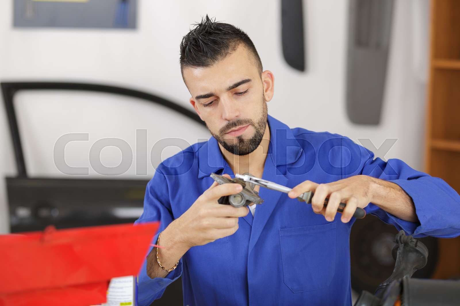 man fixing a piece in a cars gear box | Stock image | Colourbox