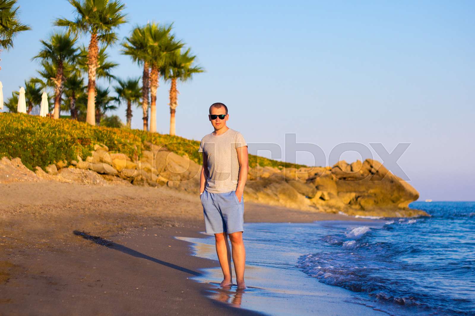 Beach travel - man standing on sandy beach | Stock image | Colourbox