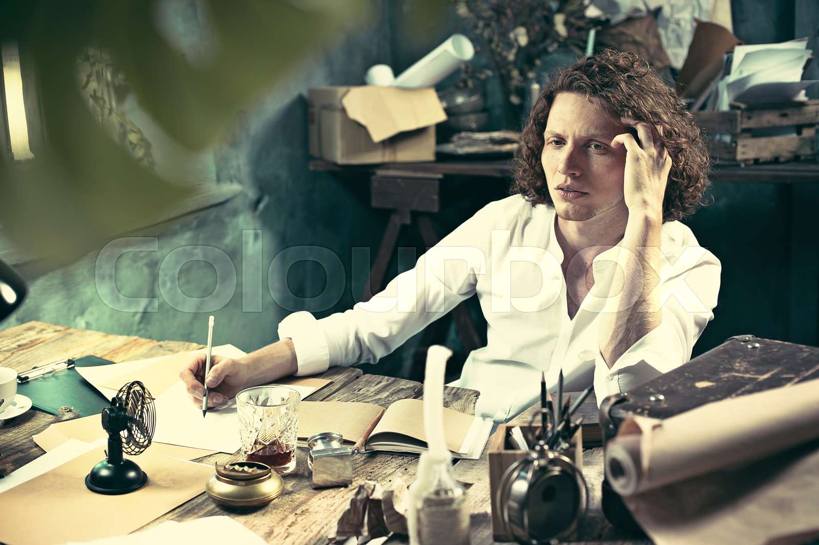 Writer at work. Handsome young writer sitting at the table and writing ...