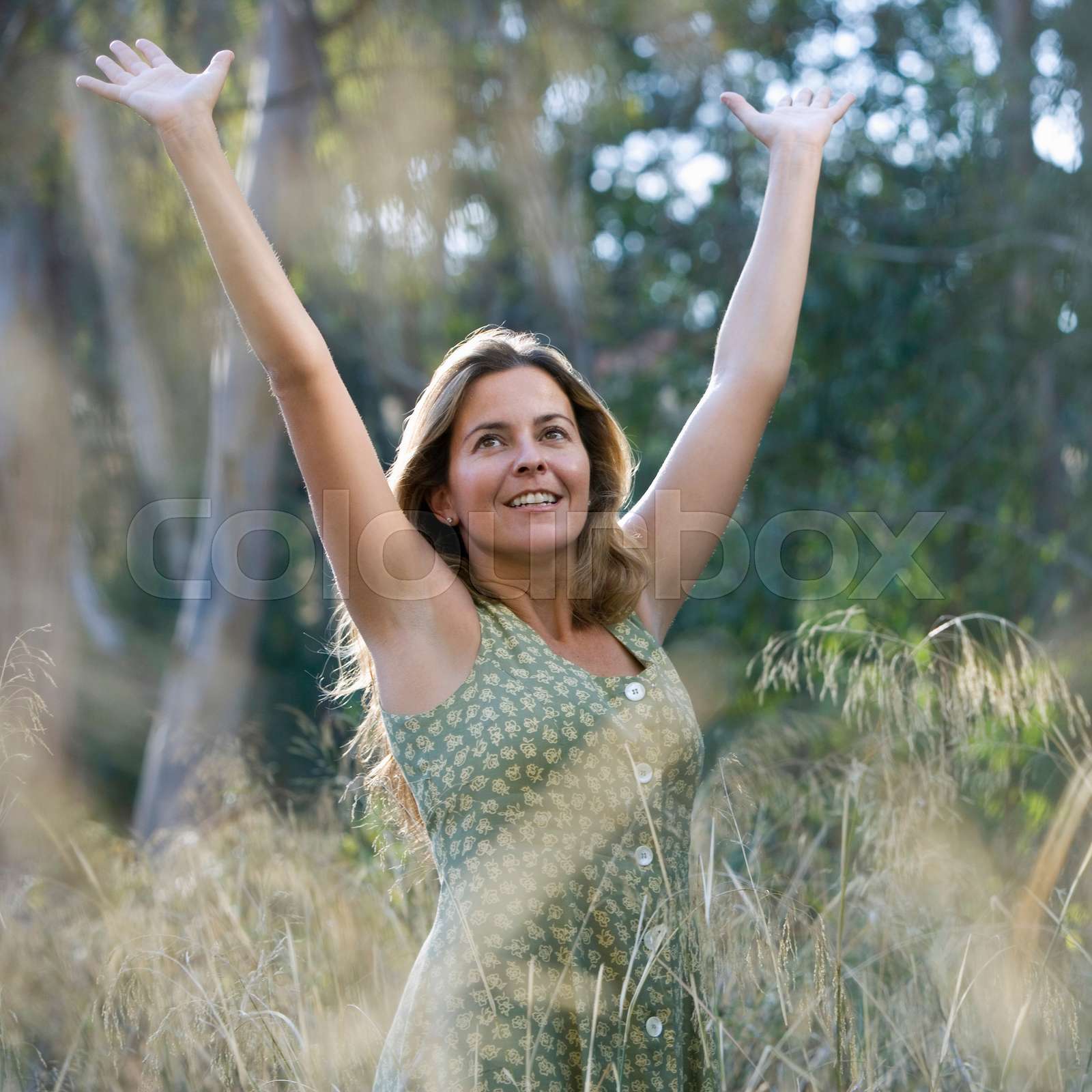 Smiling woman raising arms overhead | Stock image | Colourbox
