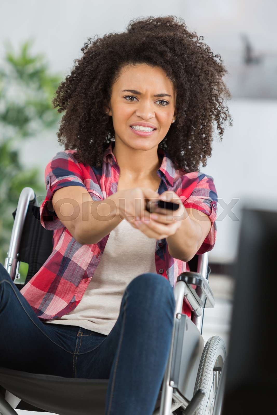 Lady in wheelchair having difficulty with remote control | Stock image ...