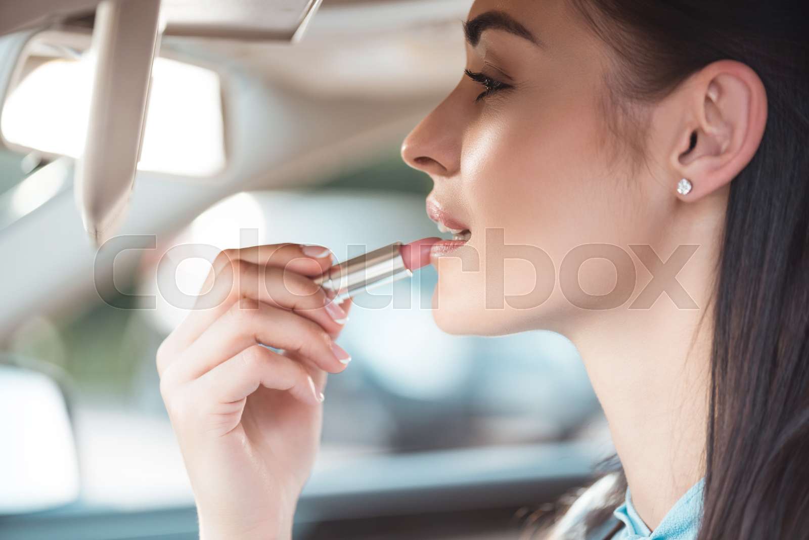 woman applying lipstick in car | Stock image | Colourbox