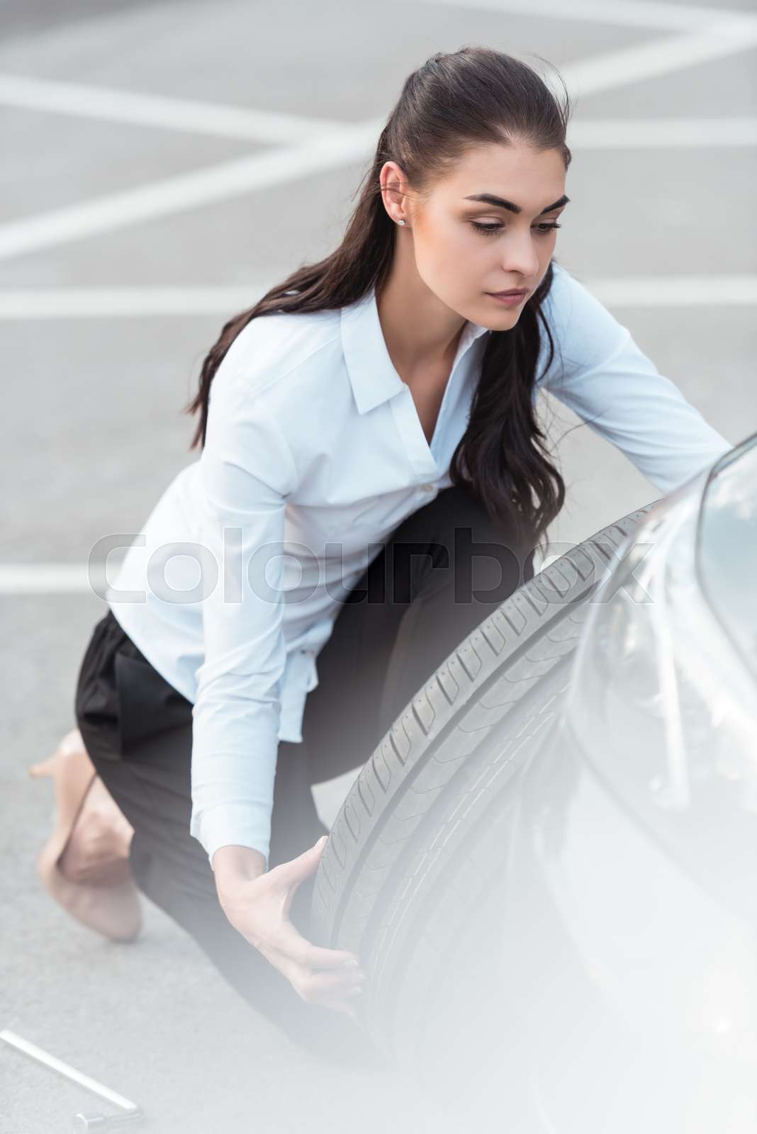 woman changing car tire | Stock image | Colourbox