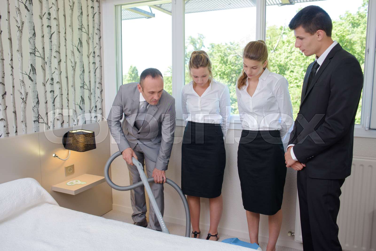 Man showing chamber maids how to vacuum | Stock image | Colourbox
