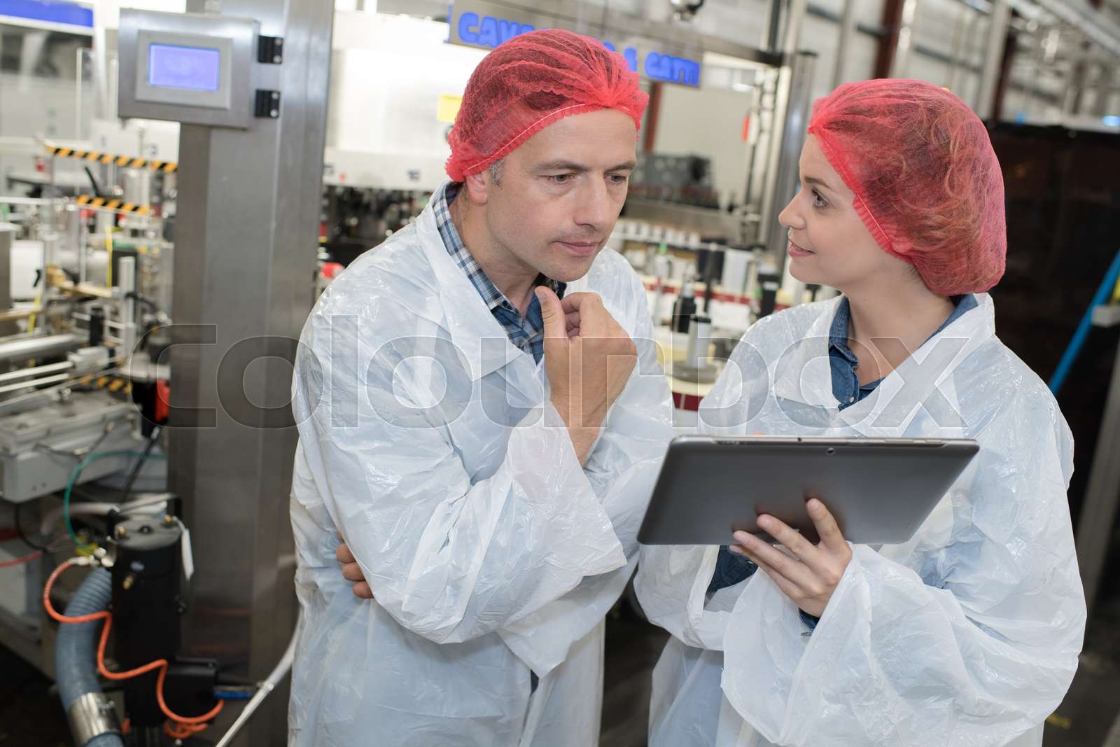 male and female factory workers in discussion holding tablet | Stock ...
