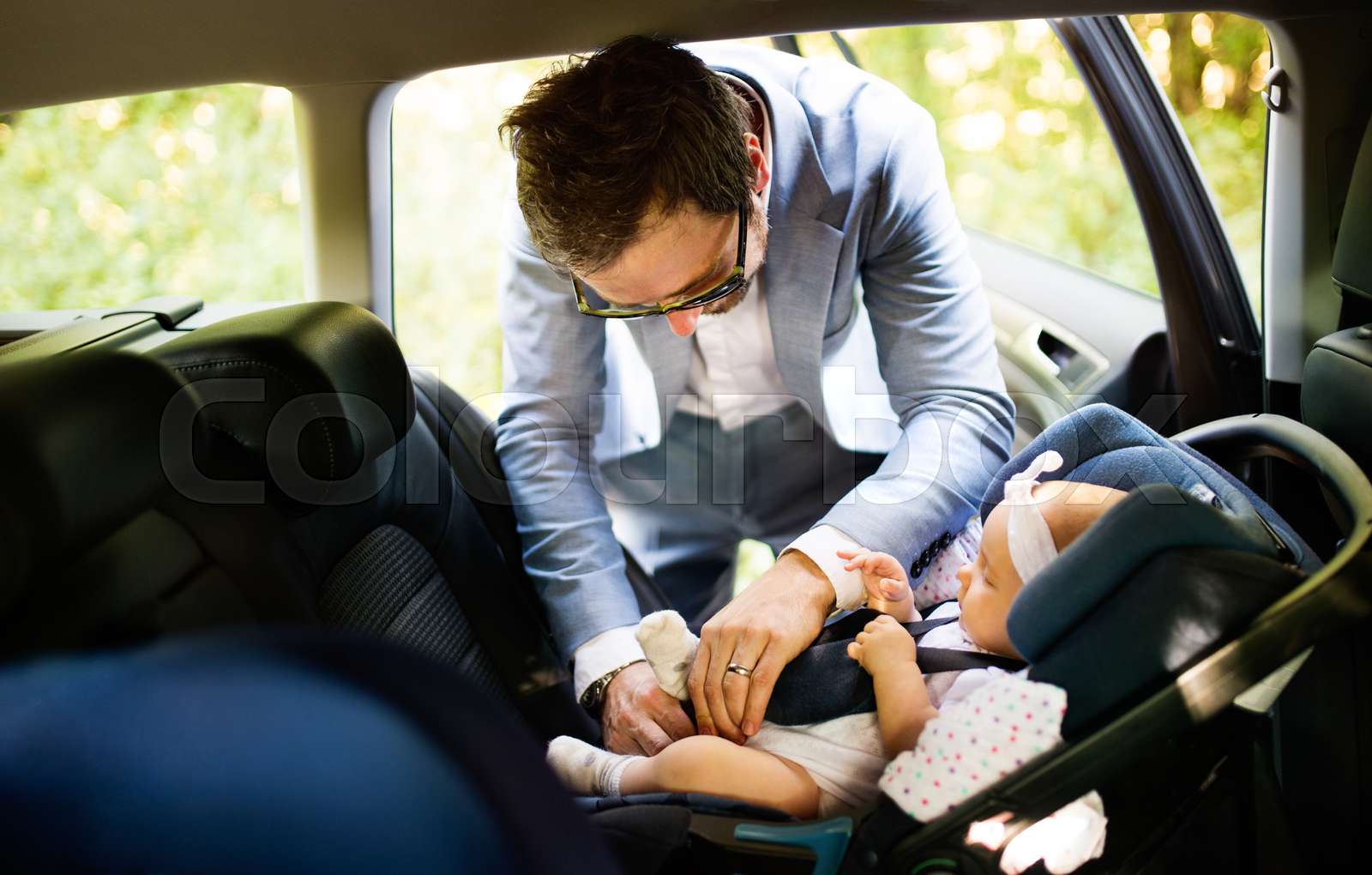 Young father putting baby girl in the car. | Stock image | Colourbox