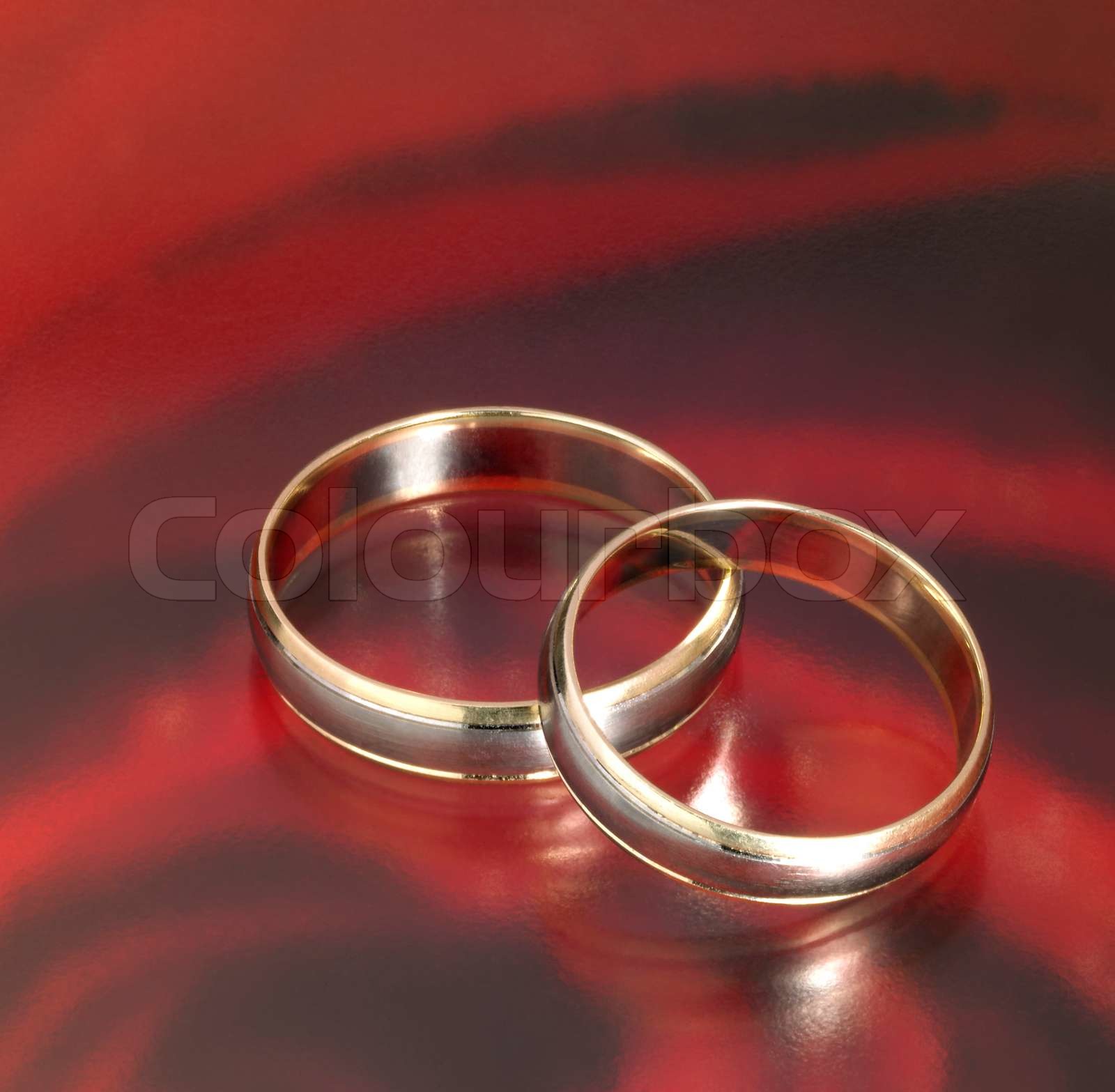 studio photography of two golden wedding rings on each other in ...