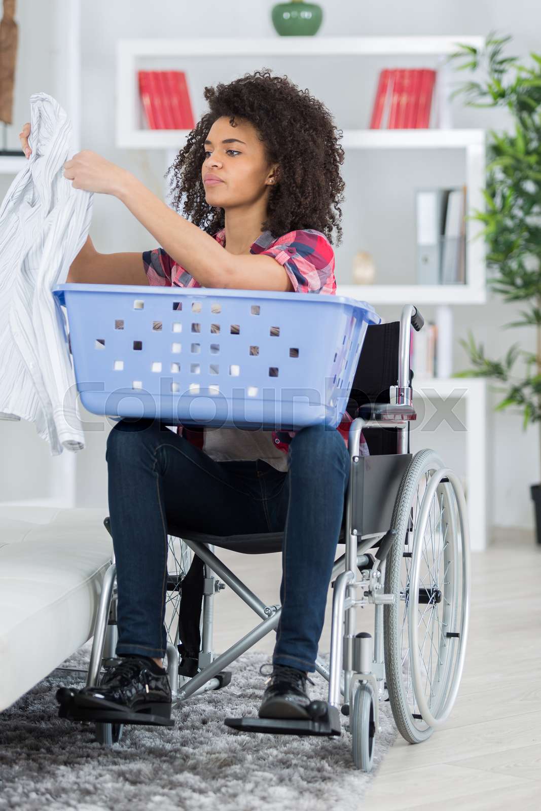 woman on the wheelchair sorting the laundry | Stock image | Colourbox