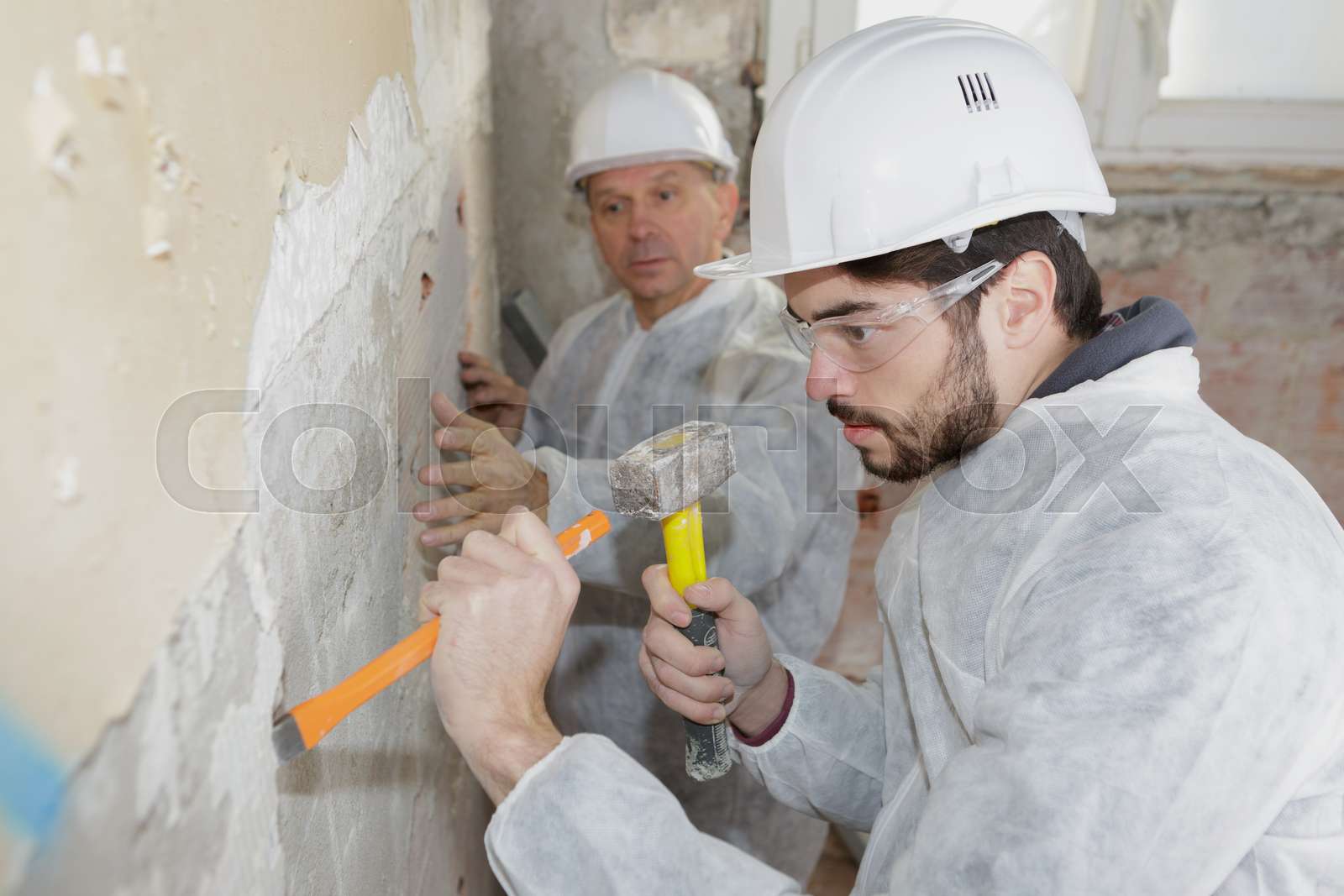 builder using hammer to remove plaster from a wall | Stock image ...
