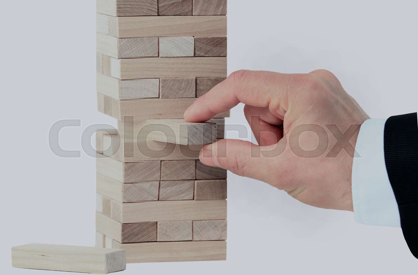 The tower from wooden blocks and man's hand take one block | Stock ...
