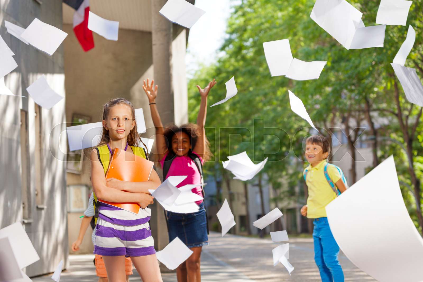 Kids throw papers in the air with school on back | Stock image | Colourbox