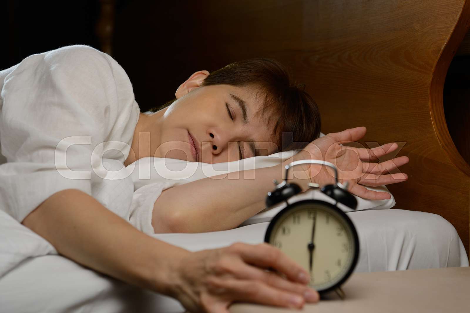 Woman turning off the alarm clock | Stock image | Colourbox