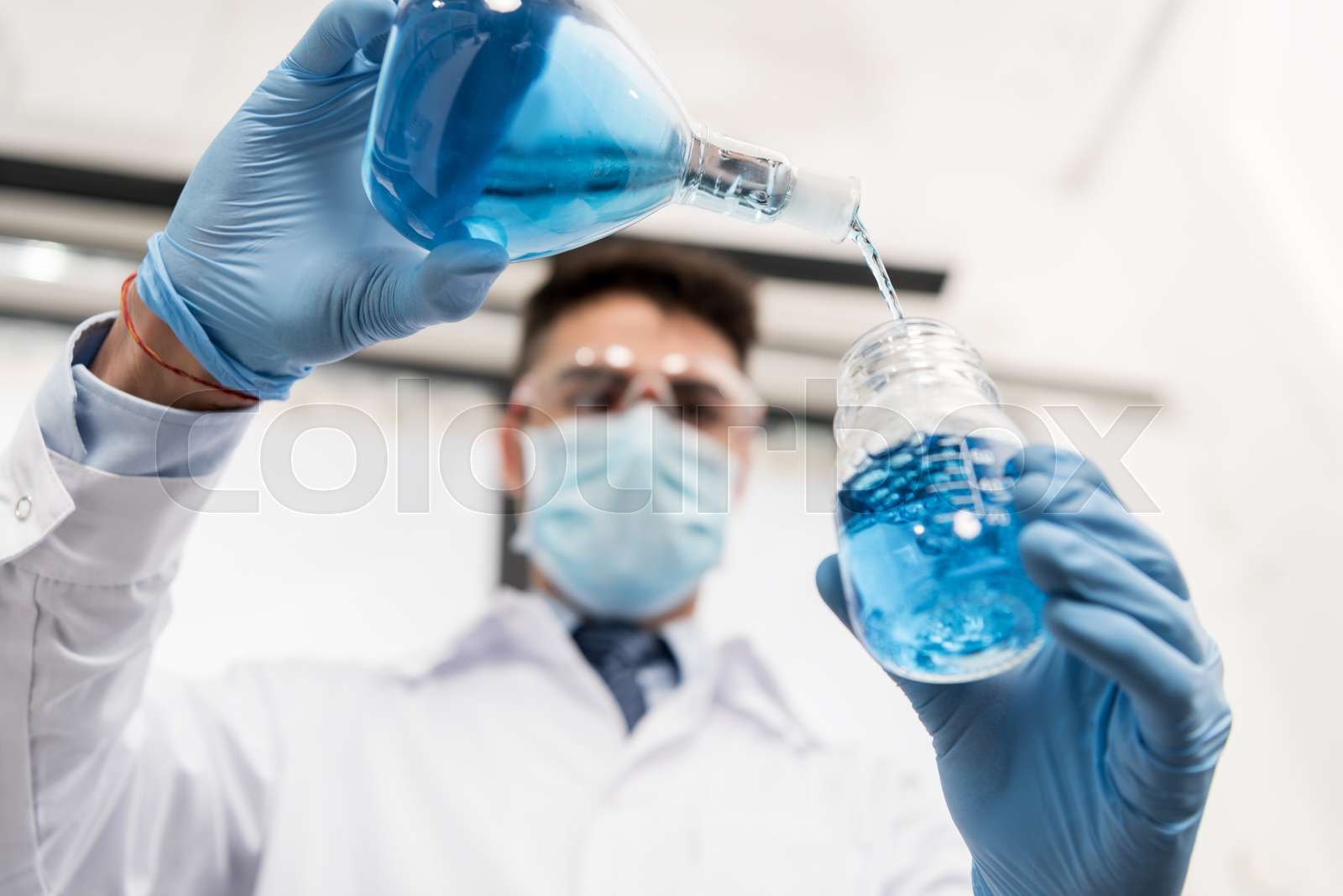 scientist pouring reagent into jar | Stock image | Colourbox