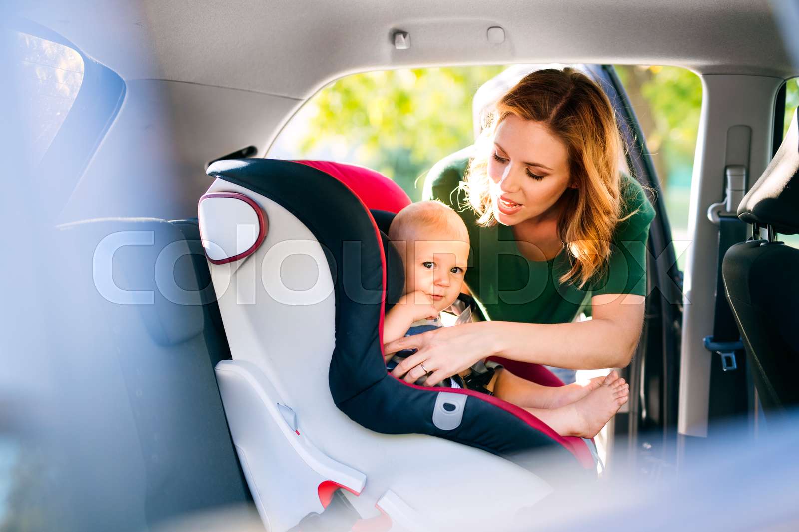 Young mother putting baby boy in the car seat. | Stock image | Colourbox