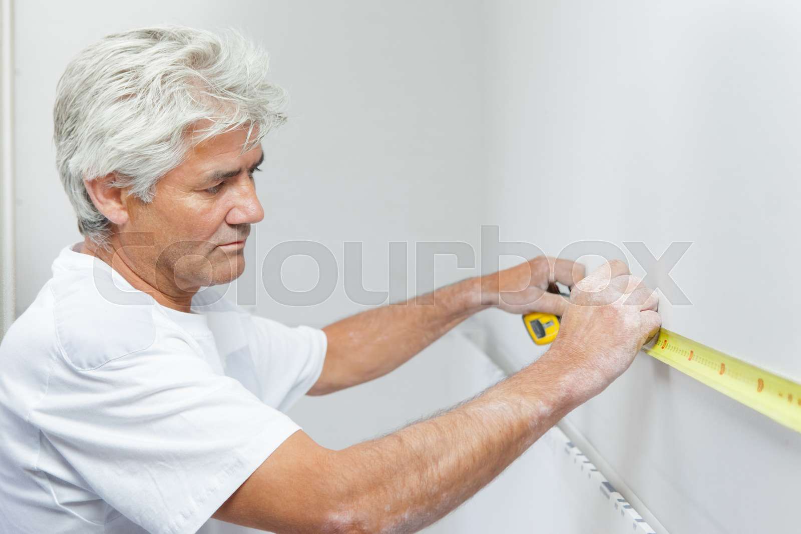 Mason measuring a white wall | Stock image | Colourbox