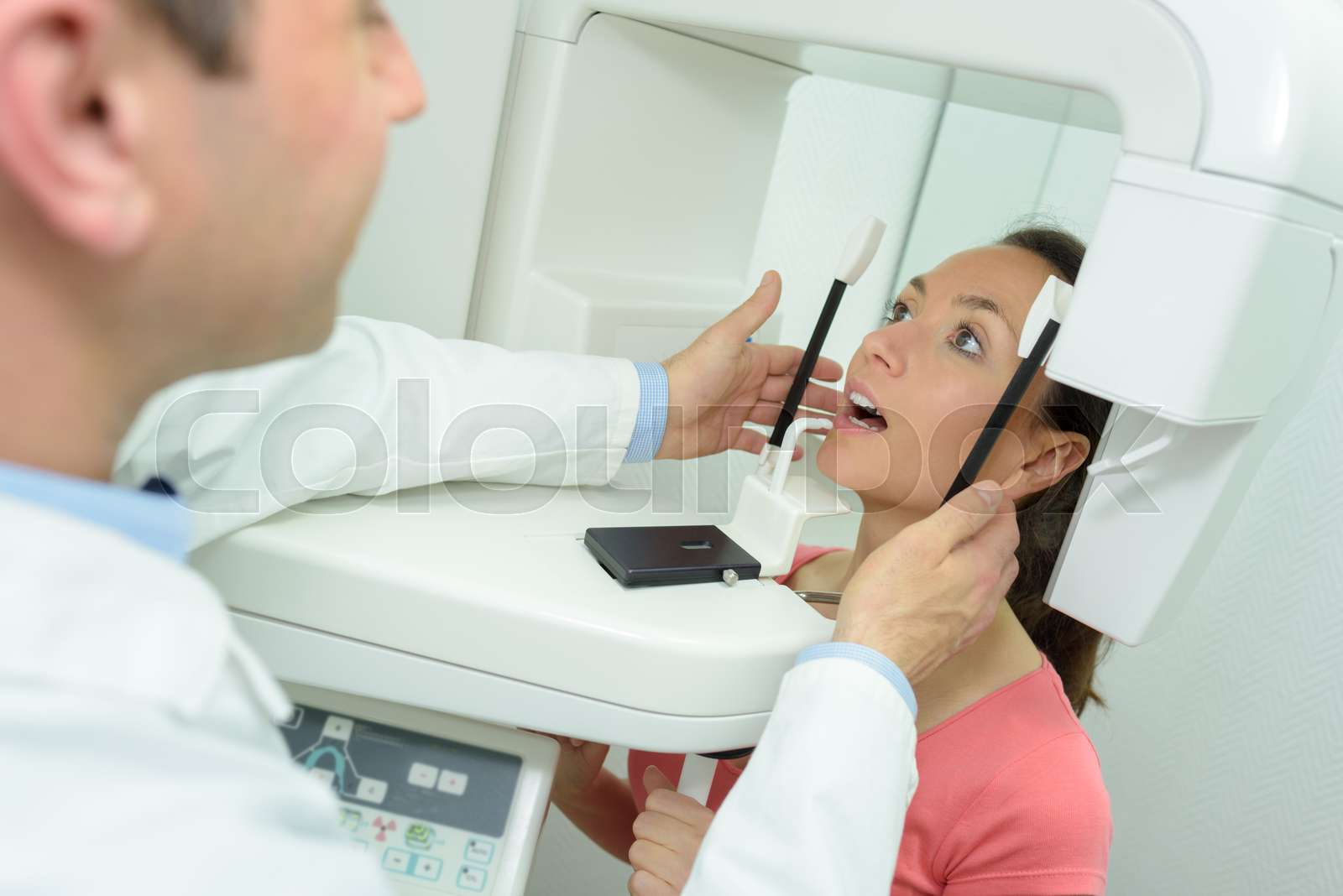 dentist directing x-ray machine at dental clinic | Stock image | Colourbox