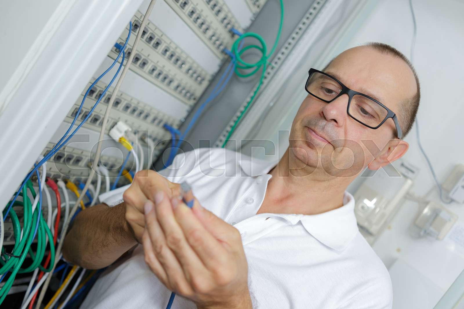 mature electrician working with cables and wires | Stock image | Colourbox