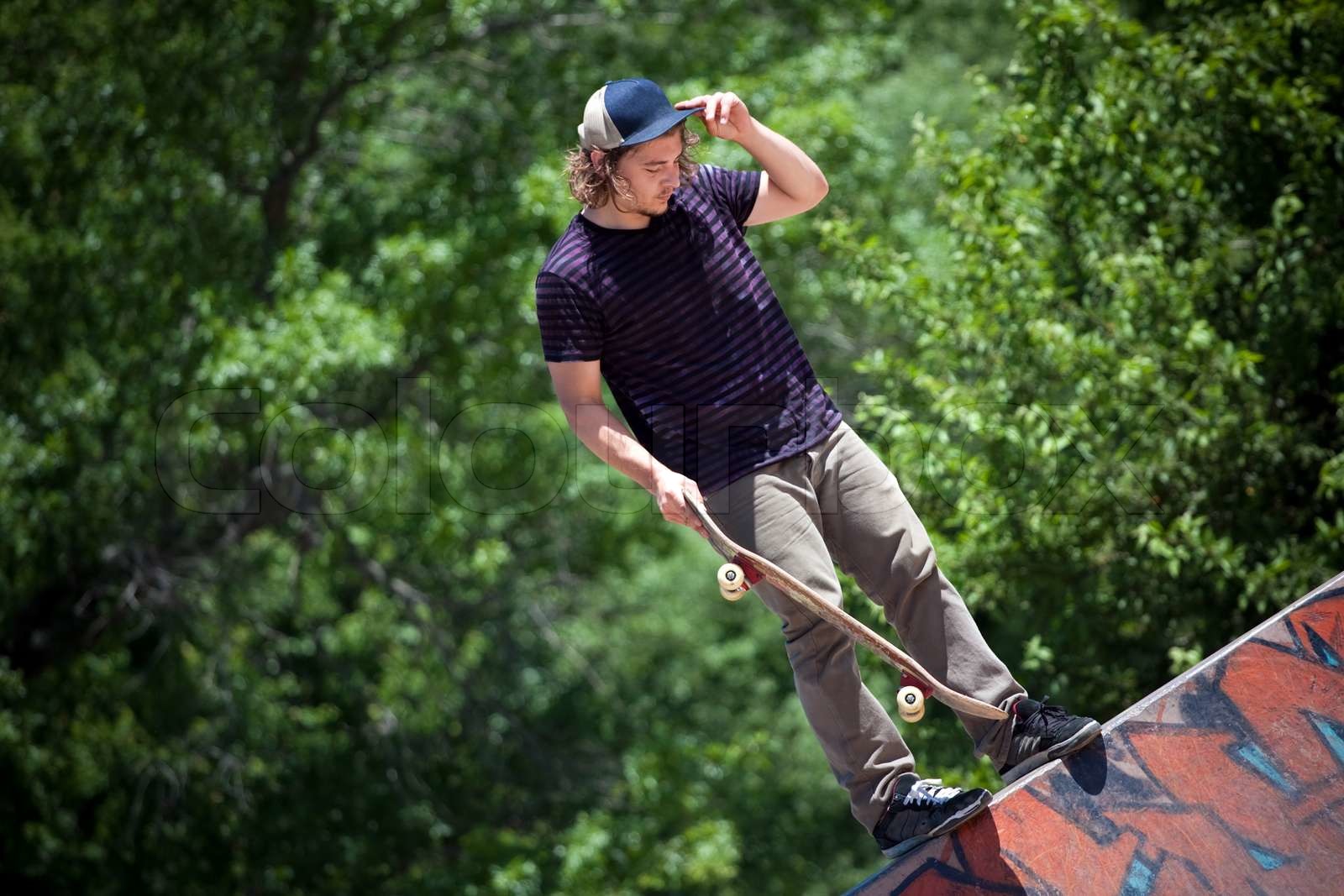 A skateboarder standing atop the skate park ramp taking a rest | Stock ...
