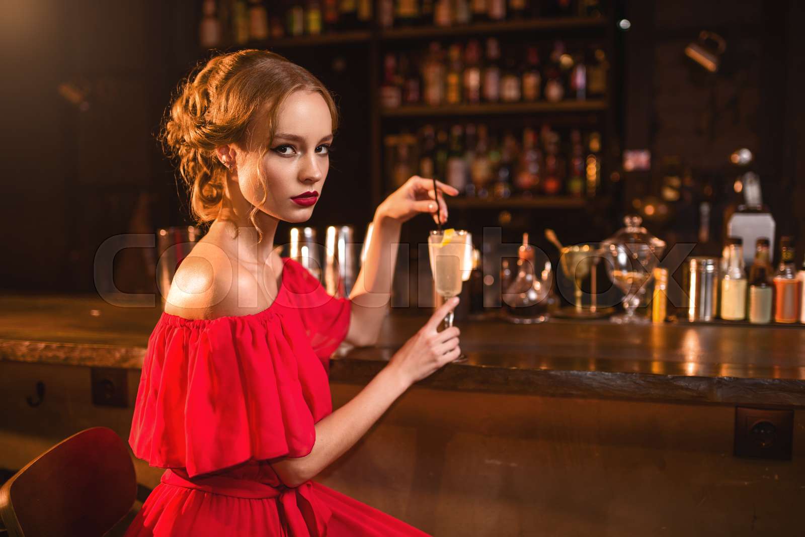 Woman in red dress drinks cocktail at bar counter | Stock image | Colourbox