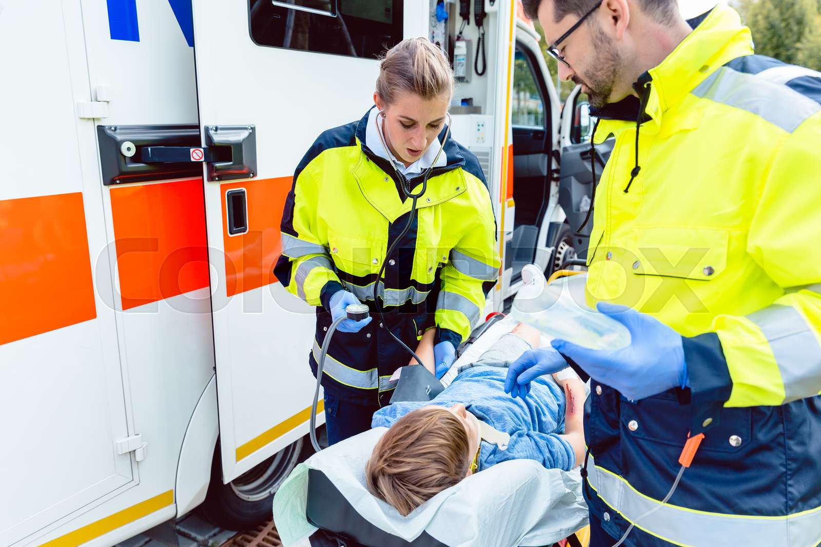 Paramedics measuring blood pressure of injured boy | Stock image ...