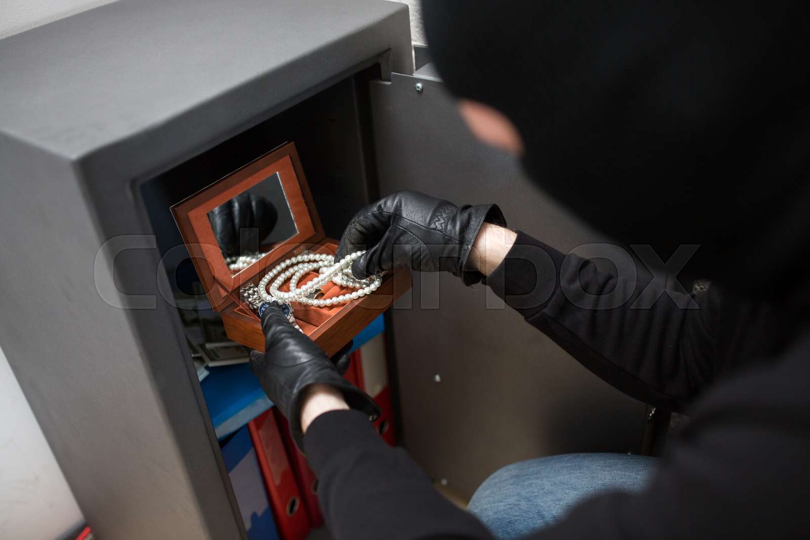 thief stealing valuables from safe at crime scene | Stock image | Colourbox