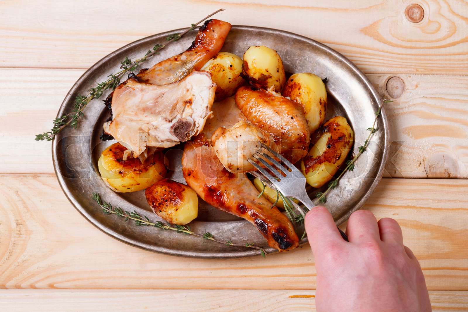 hand with fork against roasted chicken with potatoes | Stock image ...