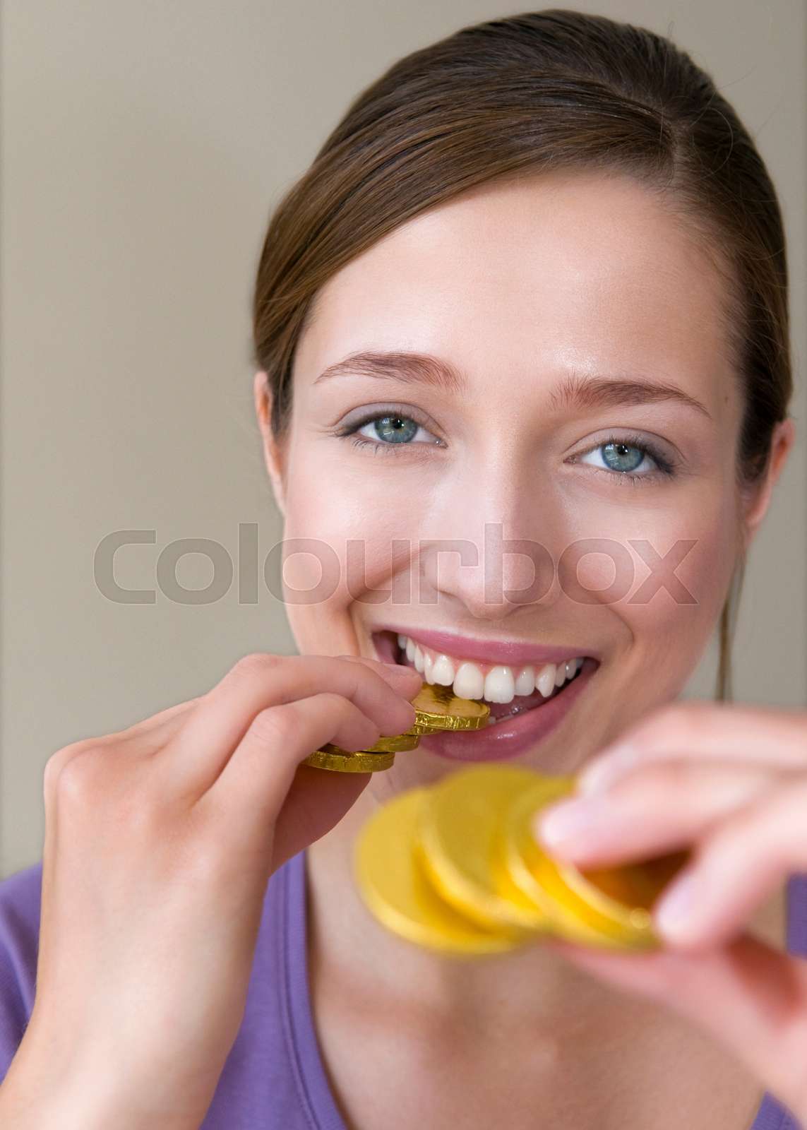 Woman bites on gold coins | Stock image | Colourbox