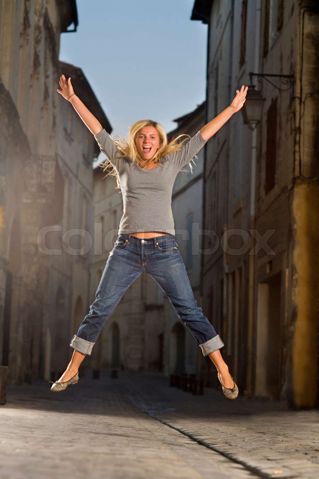 Young woman jumps in street at dusk | Stock image | Colourbox