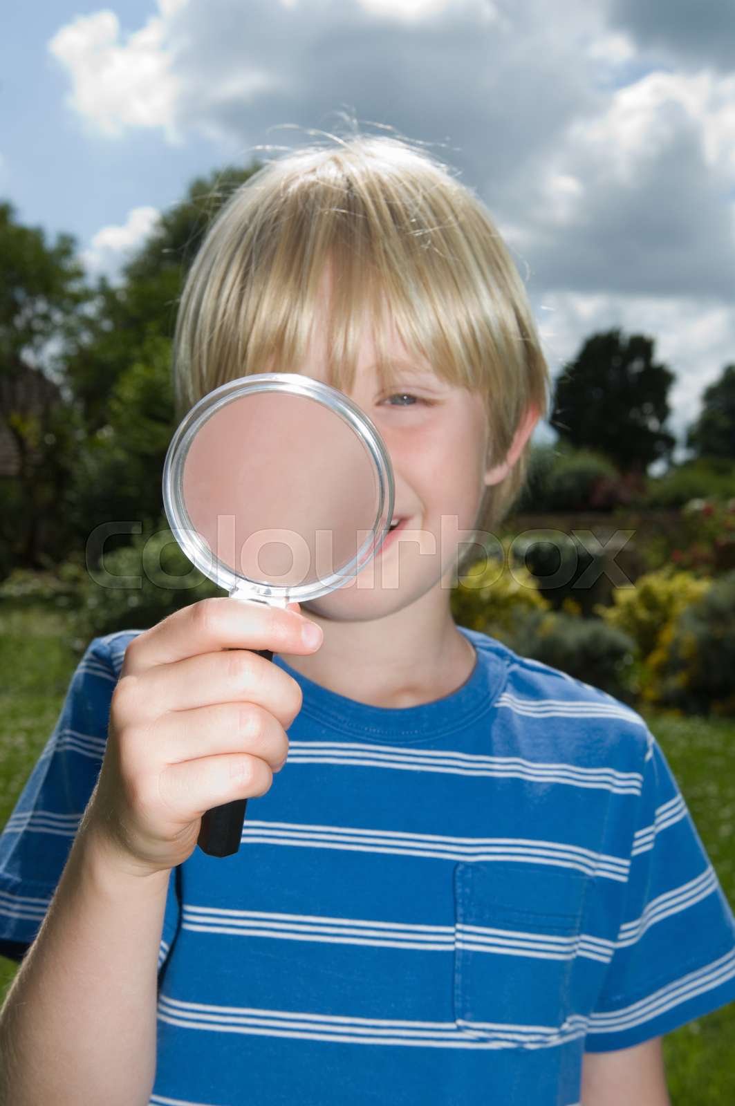 Boy using magnifying glass outdoors | Stock image | Colourbox