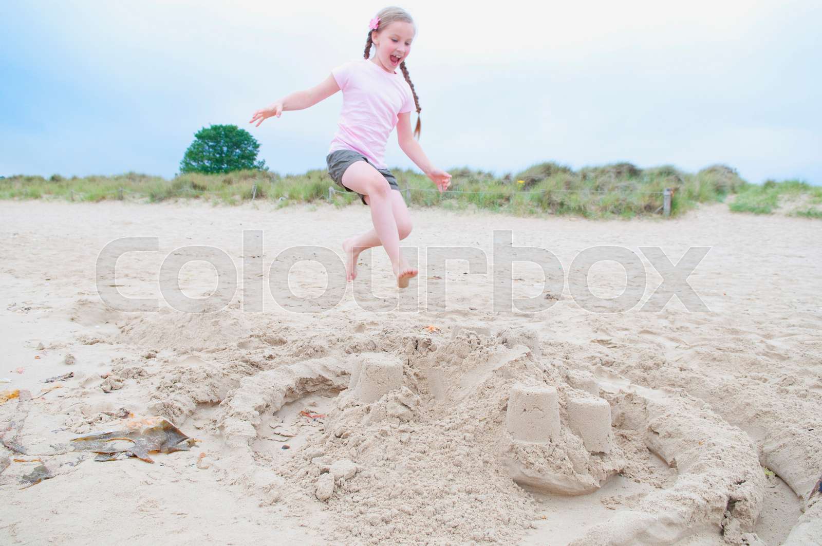 Girl destroying sand castle on beach | Stock image | Colourbox