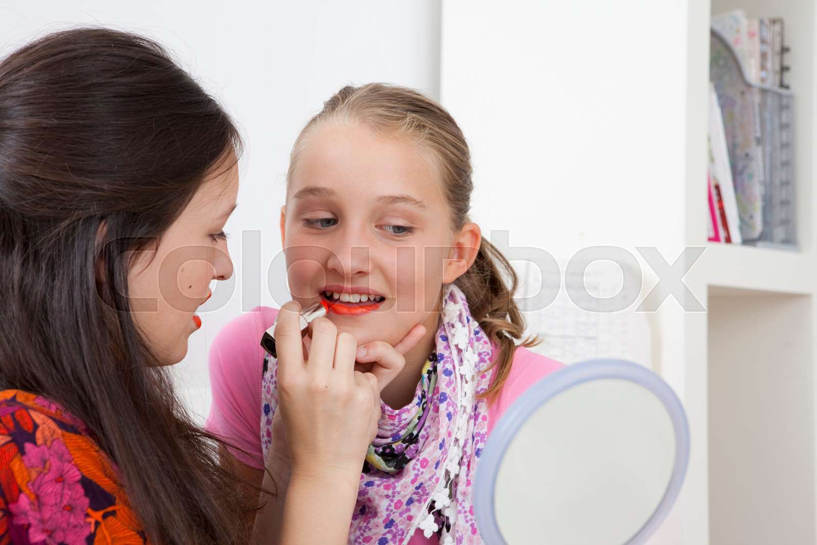 Girl putting lipstick on friend | Stock image | Colourbox