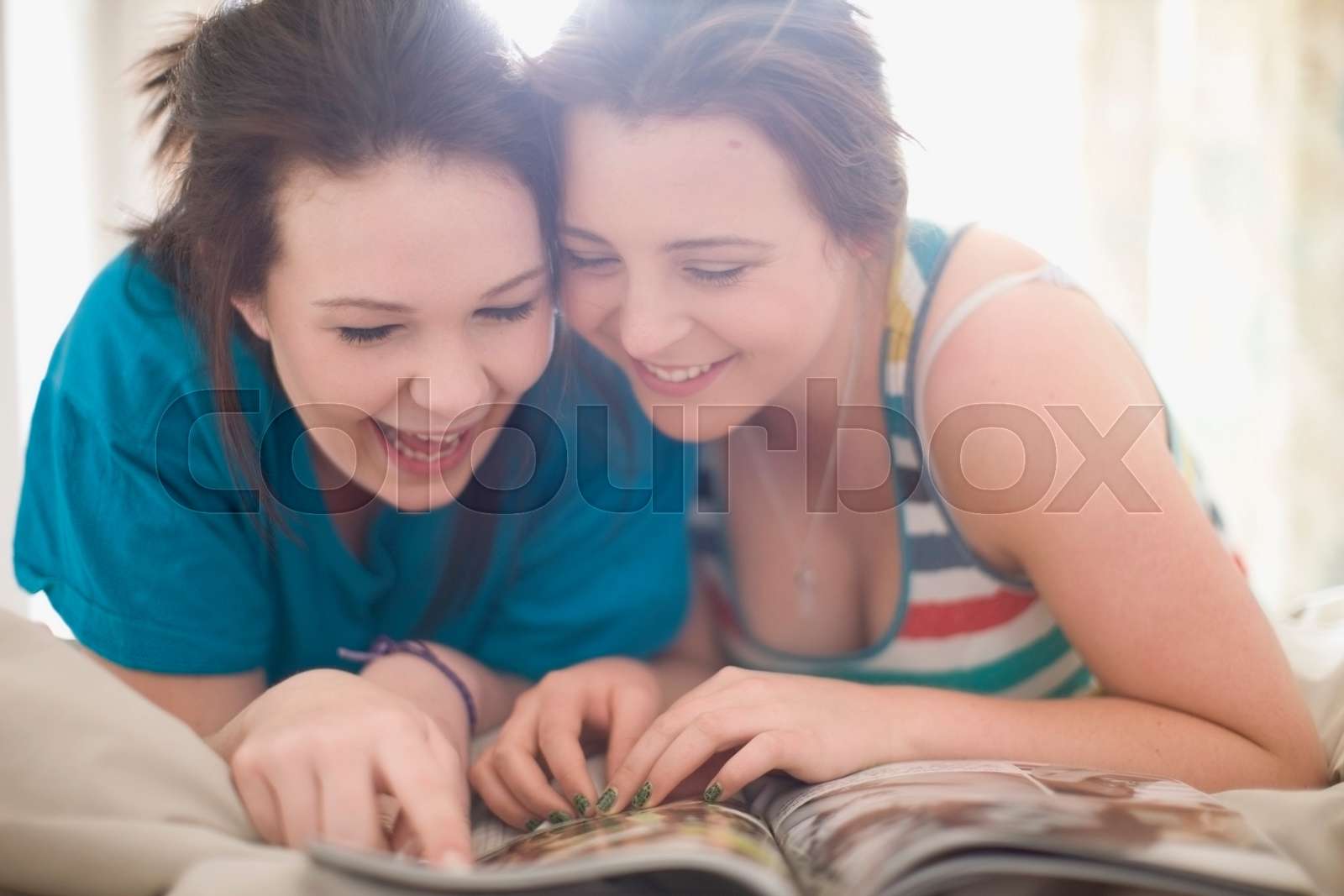 Teenage girls reading magazine together | Stock image | Colourbox