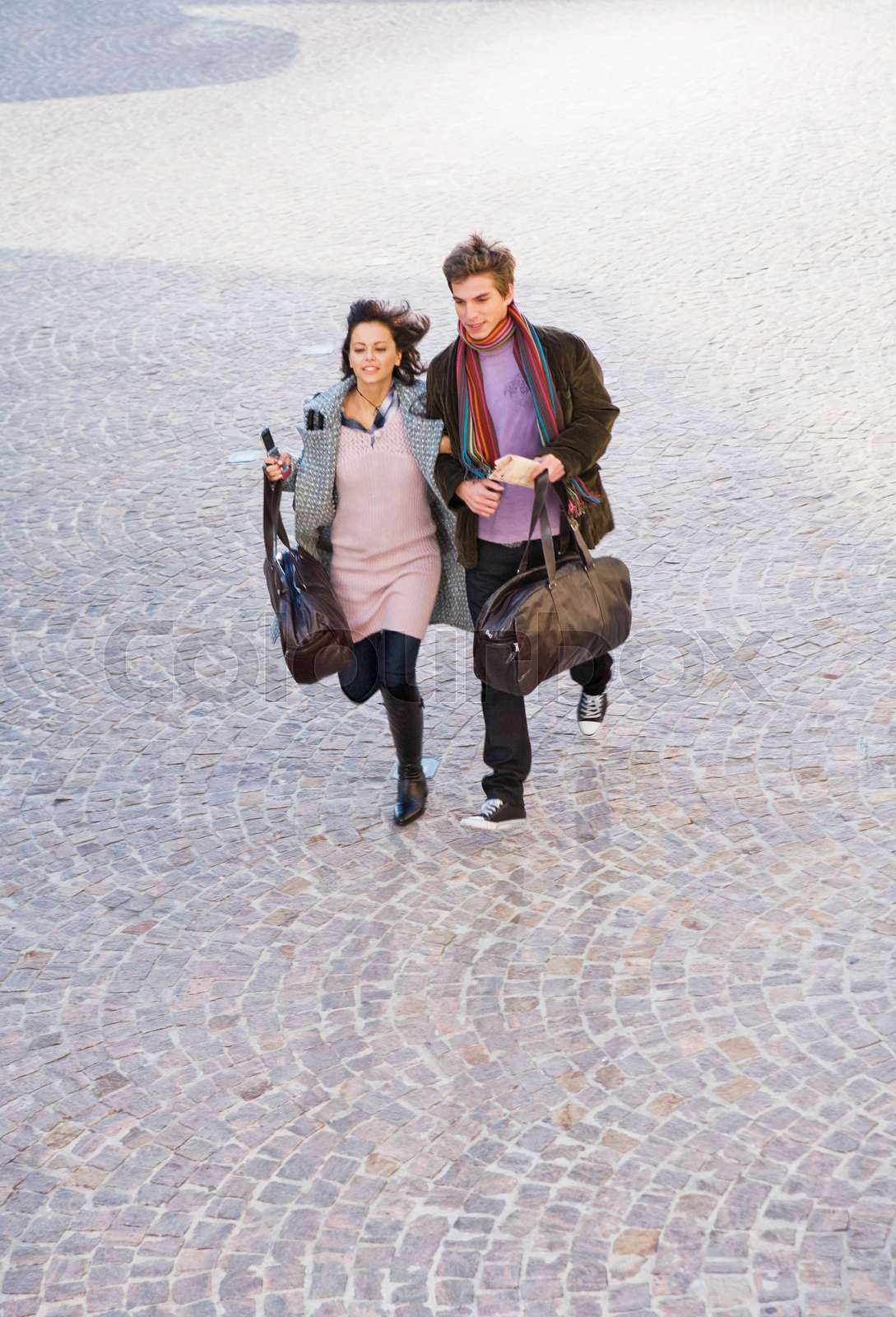 Man and woman arm in arm carrying bags | Stock image | Colourbox
