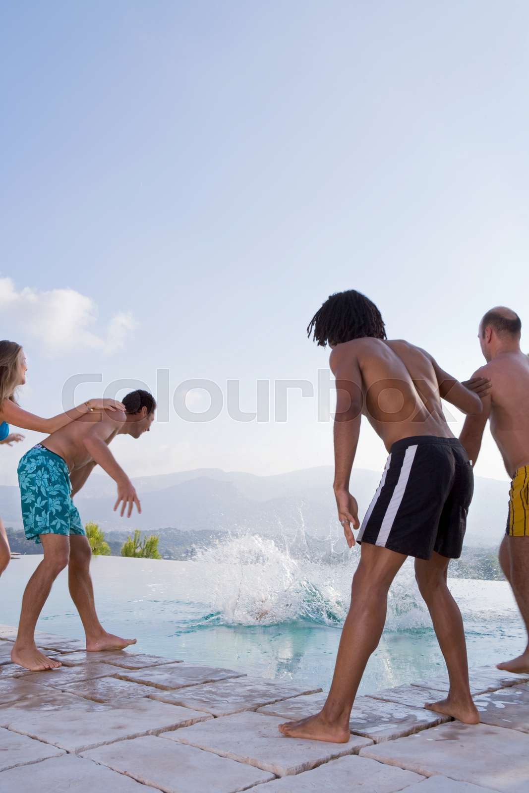 Men and women throw a friend into a pool | Stock image | Colourbox