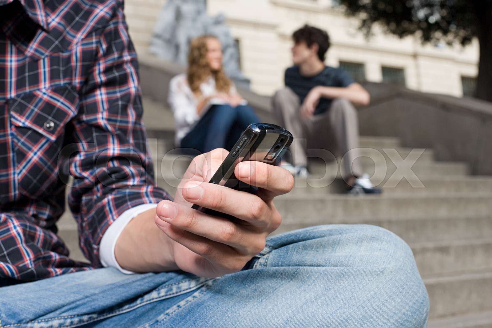Boy text messaging on stairway | Stock image | Colourbox
